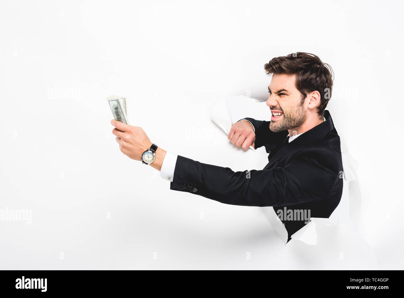 angry businessman holding dollar banknotes behind hole in paper wall on ...