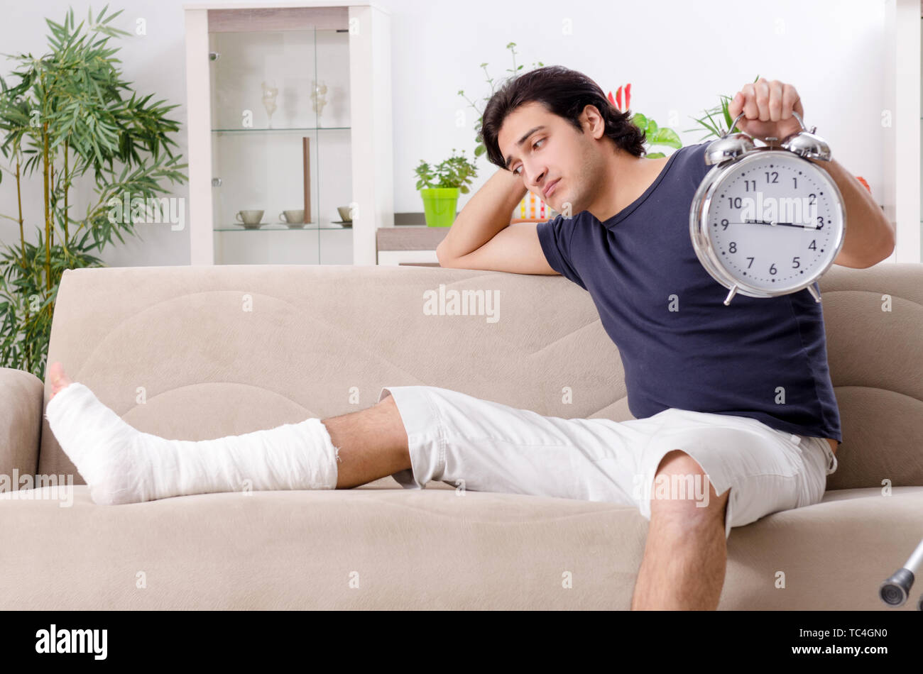 Leg injured young man suffering at home Stock Photo - Alamy