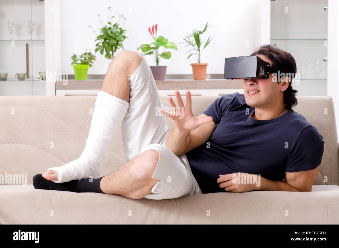 Leg injured young man suffering at home Stock Photo - Alamy