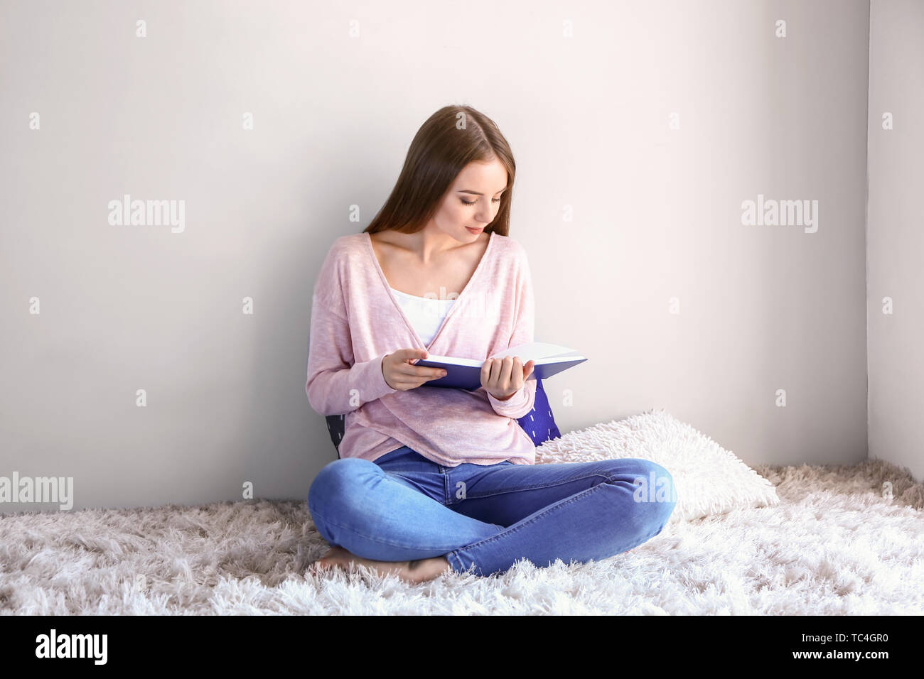 Beautiful young woman reading book at home Stock Photo - Alamy