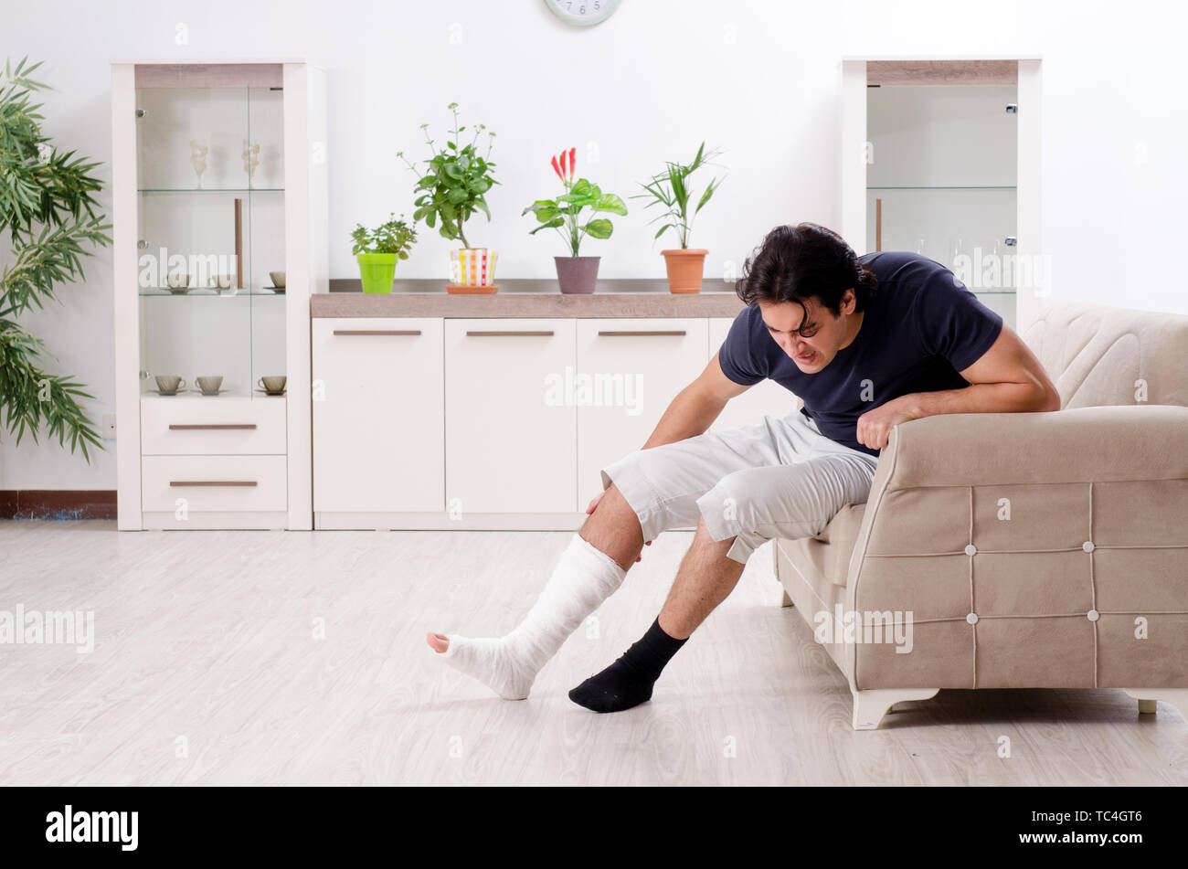 Leg injured young man suffering at home Stock Photo - Alamy