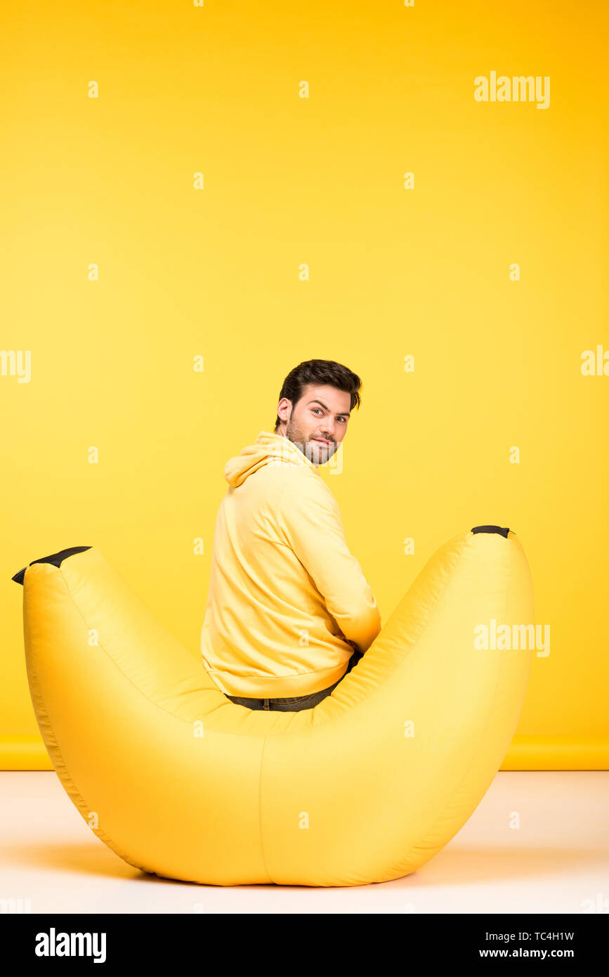 man sitting on bean bag chair on yellow and looking at camera Stock ...