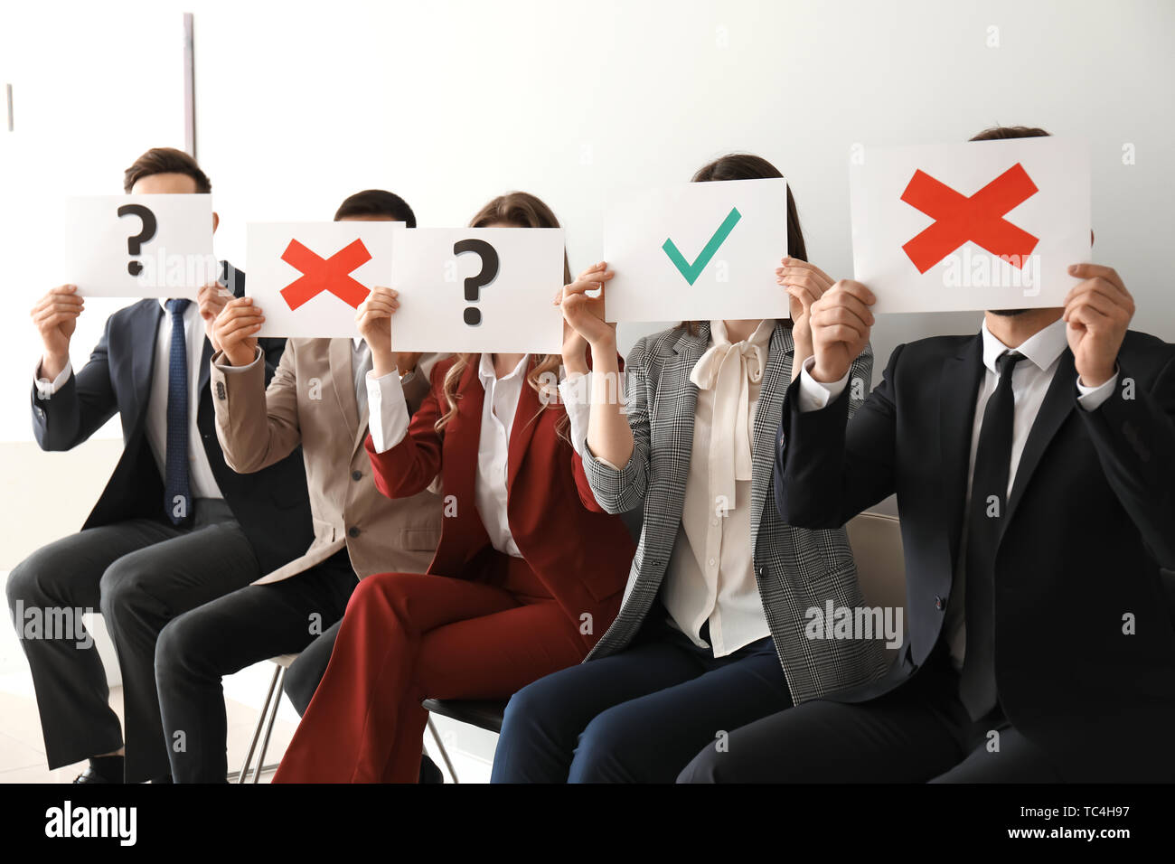 Young people holding paper sheets with different marks while sitting on ...