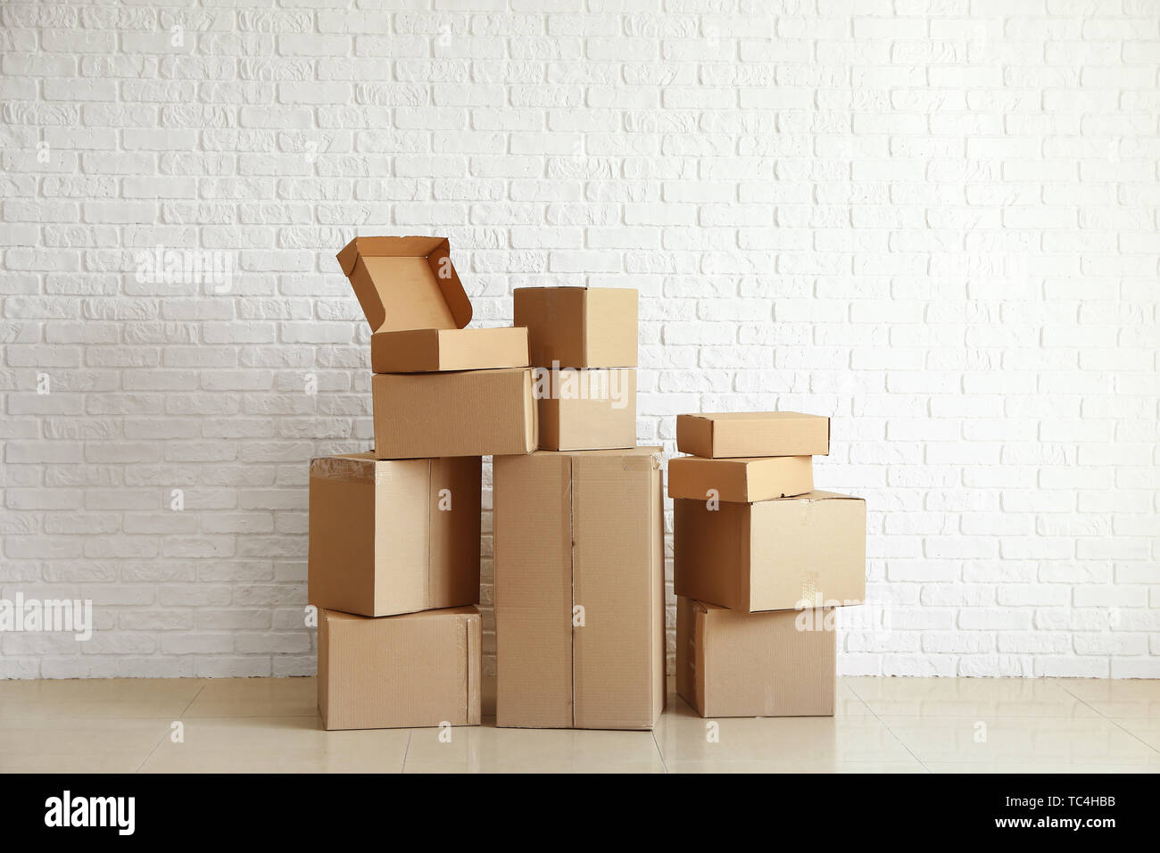 Cardboard boxes near white brick wall Stock Photo - Alamy