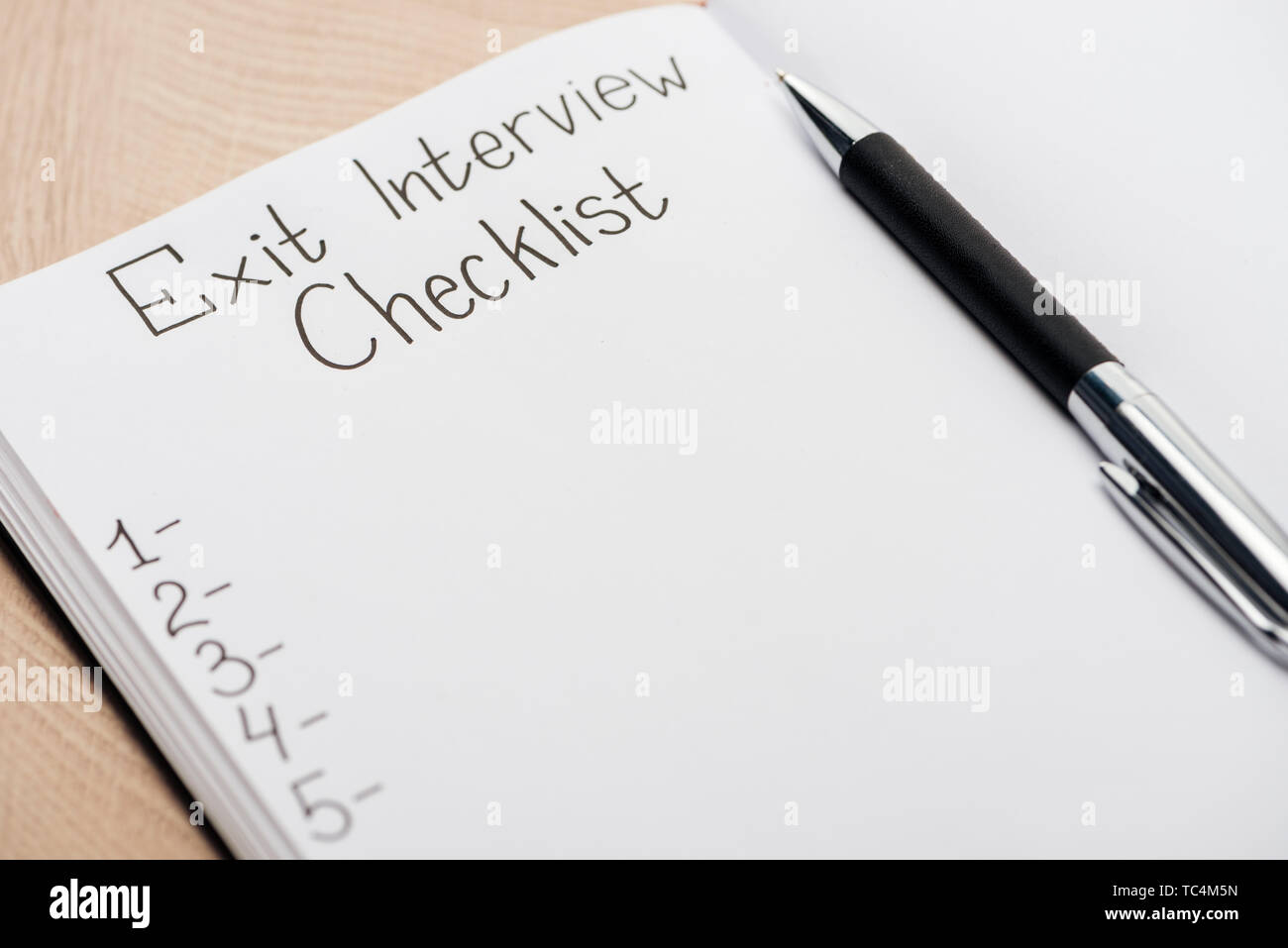 close up of notebook with exit interview checklist lettering and pen ...