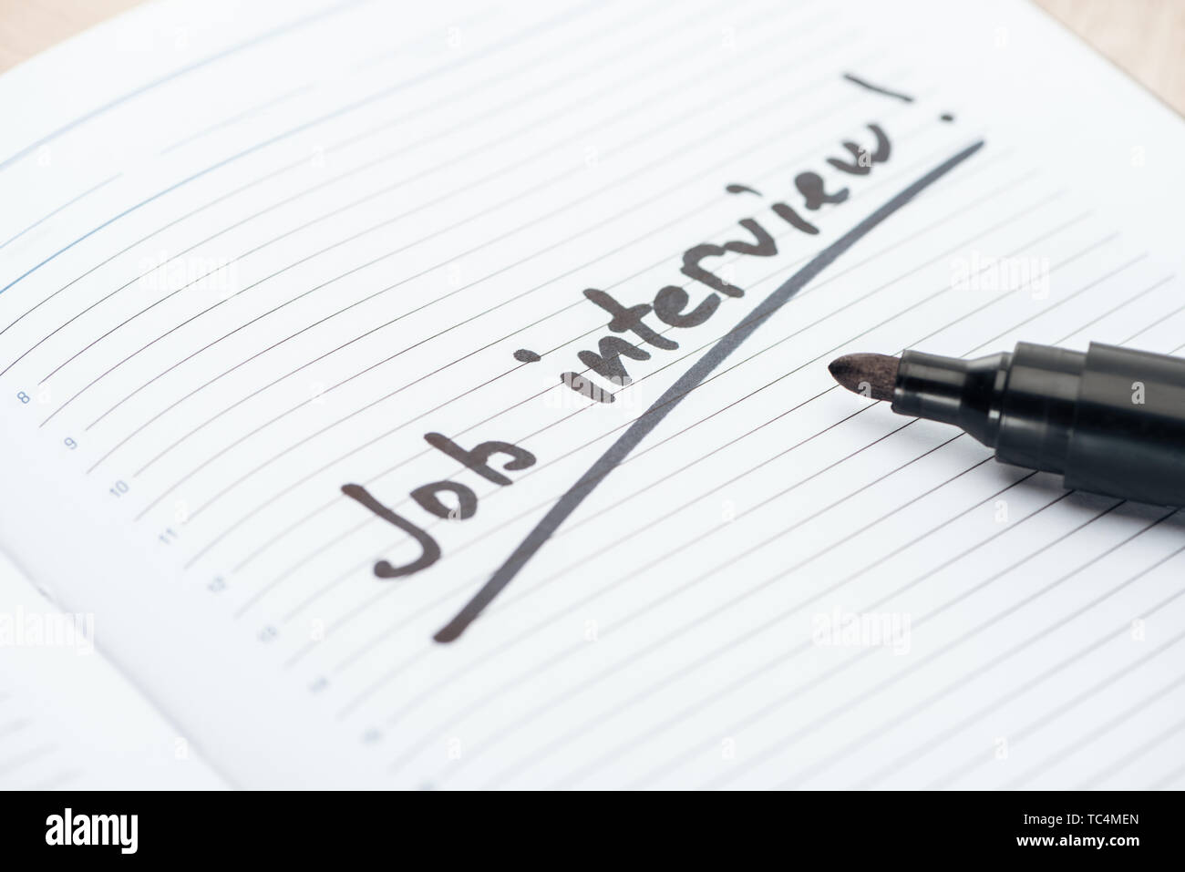 close up of job interview lettering on white paper near black marker ...