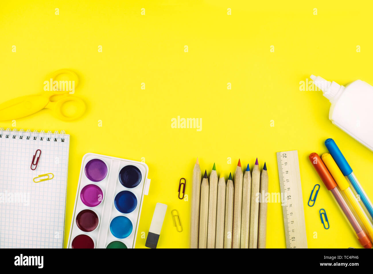 Different school supplies on bright yellow paper background. Back to ...