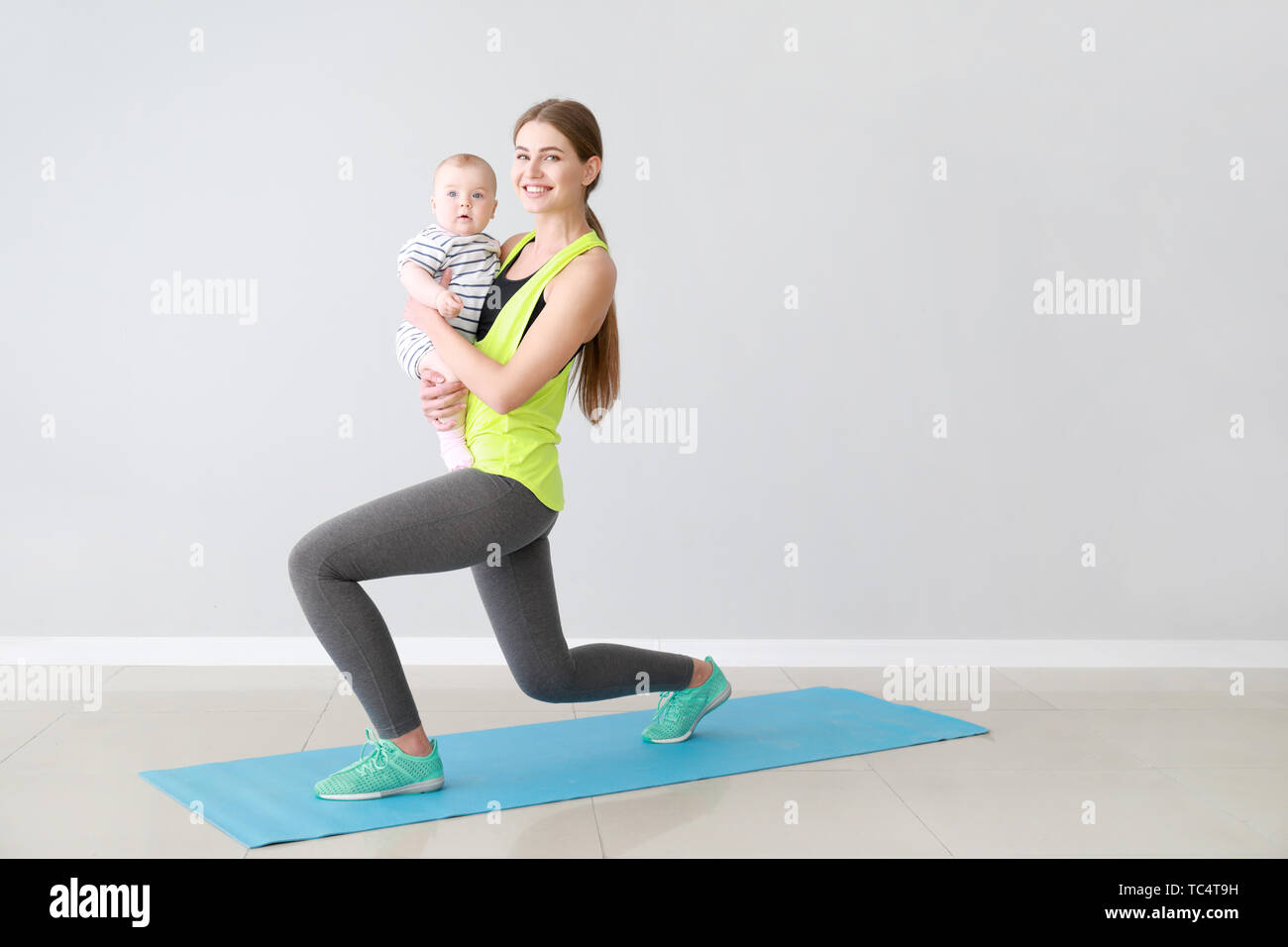 Mother training with cute little baby indoors Stock Photo - Alamy