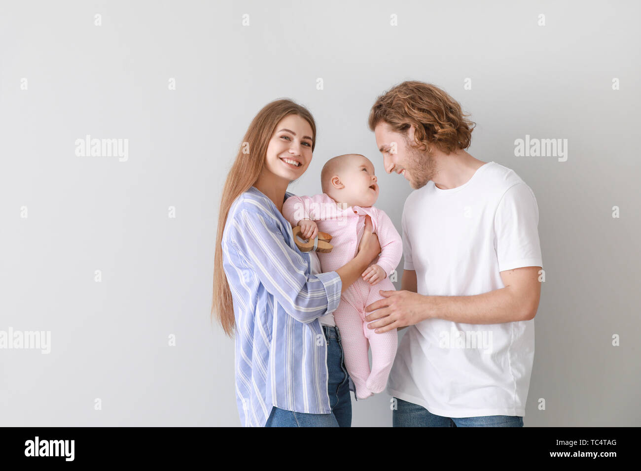 Happy parents with cute little baby on light background Stock Photo - Alamy