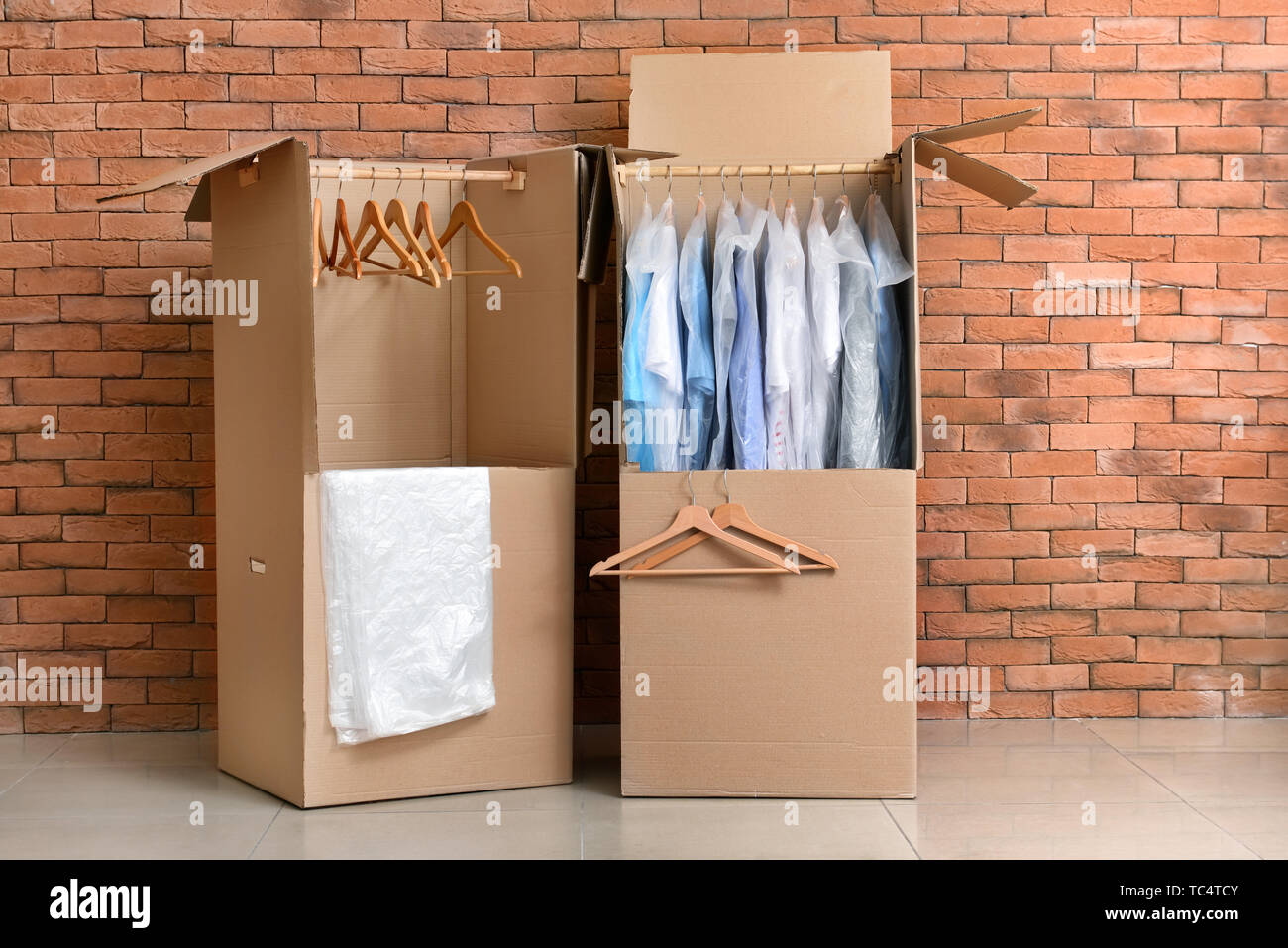Wardrobe boxes with clothes near brick wall Stock Photo - Alamy