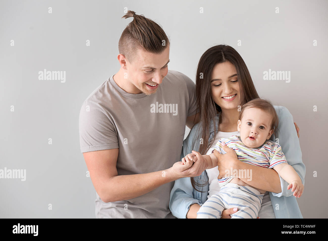 Happy parents with cute little baby on light background Stock Photo - Alamy