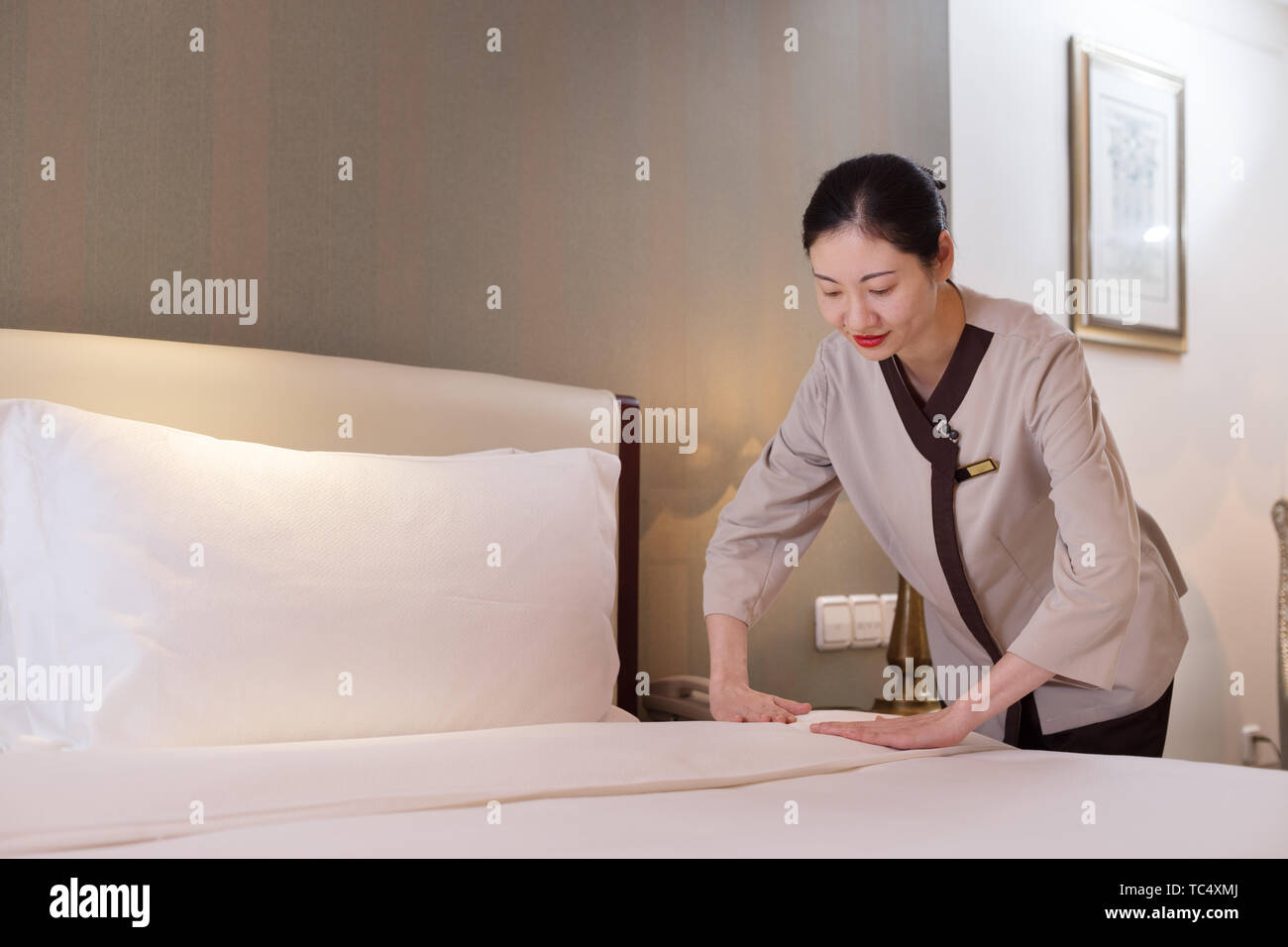 young chinese woman housekeeper makes bed in modern hotel Stock Photo ...
