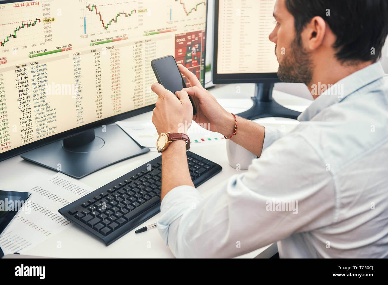 Texting to client. Side view of young bearded trader in formal wear ...