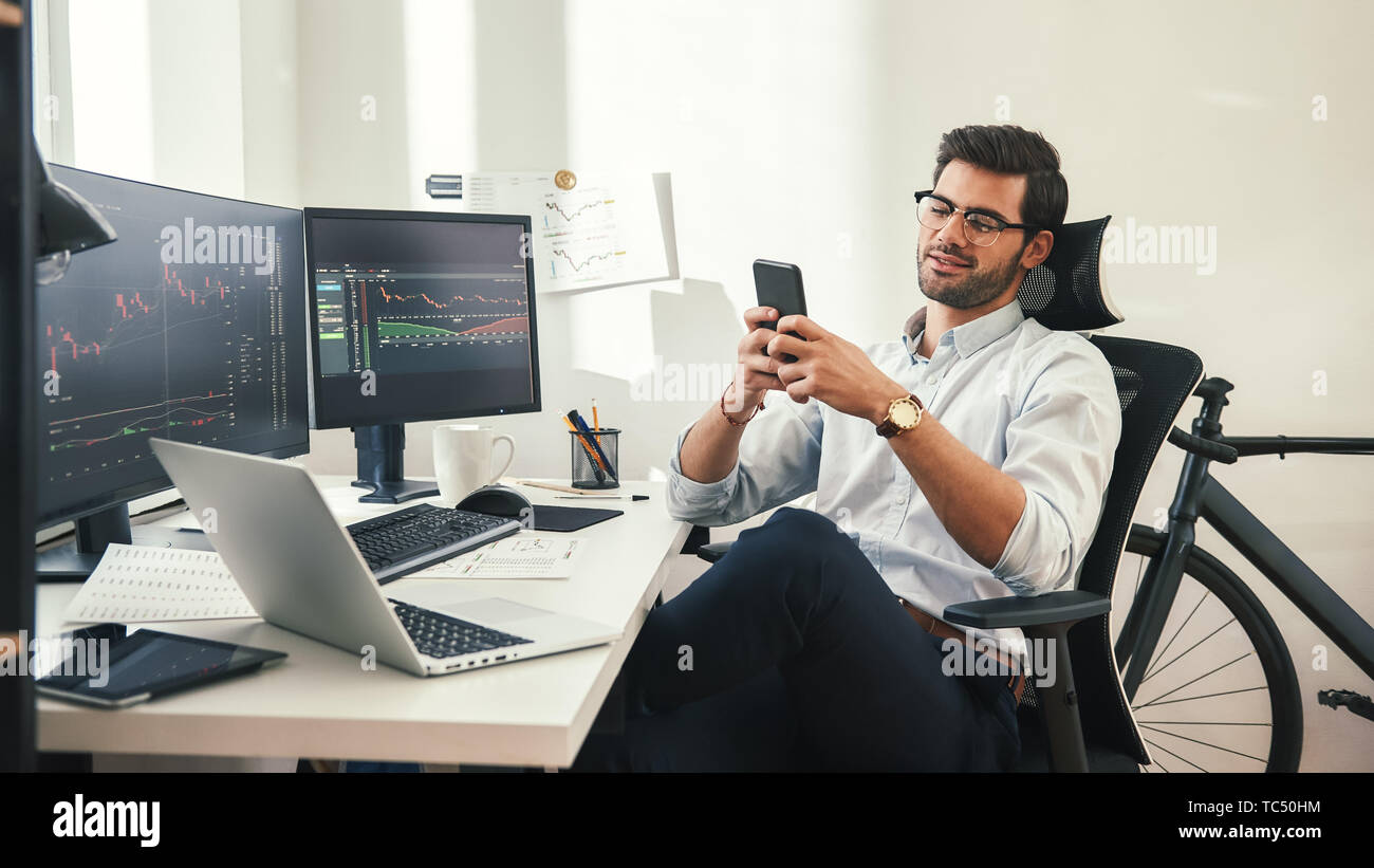 Using modern technologies. Relaxed young trader in formal wear and ...
