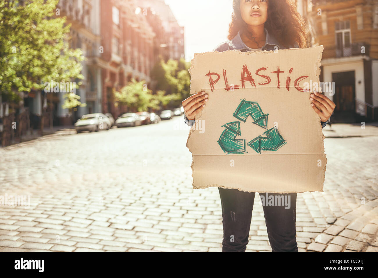 Say no to plastic. Young female activist holding a signboard with word ...