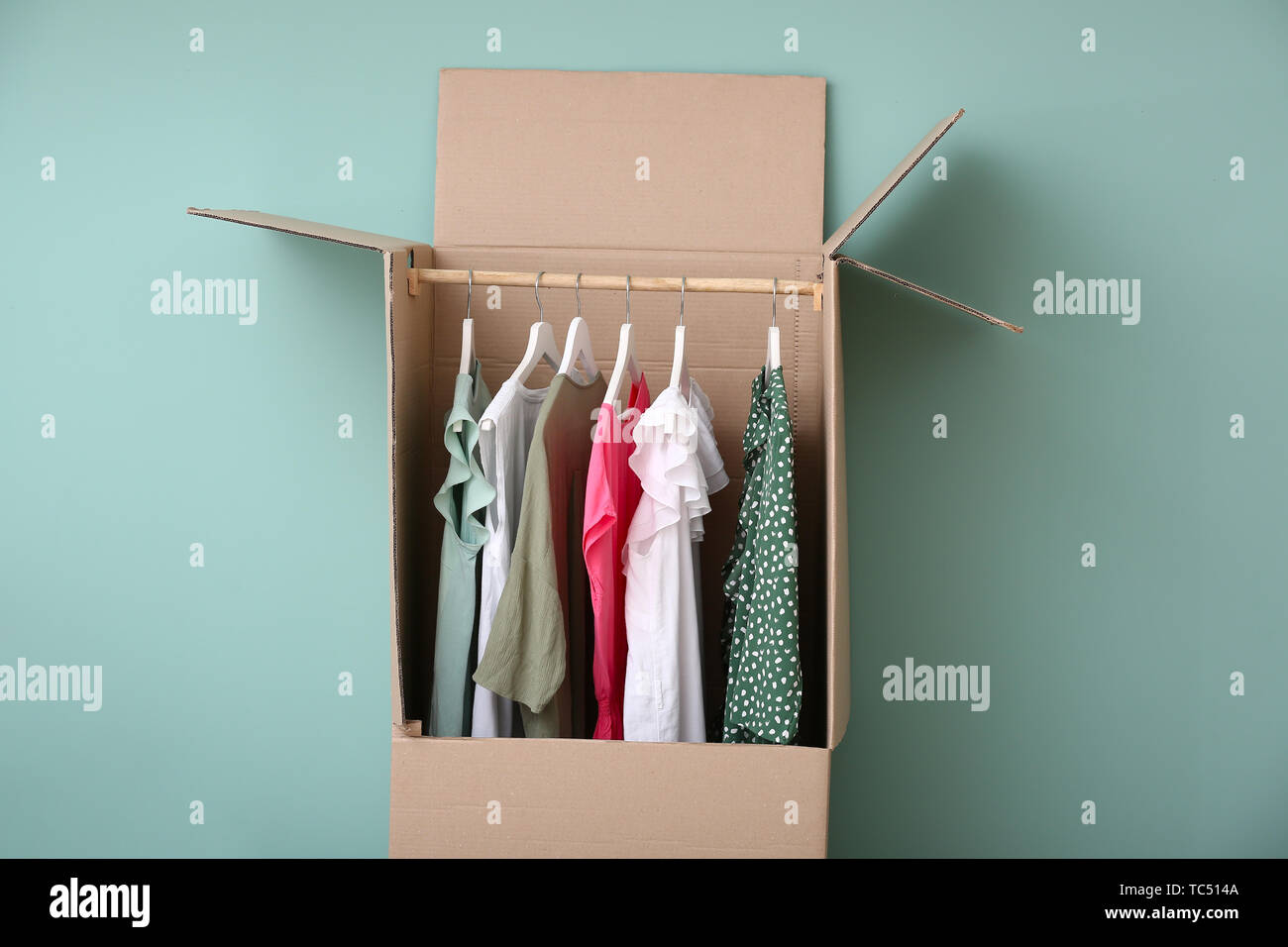 Wardrobe box with clothes on color background Stock Photo - Alamy