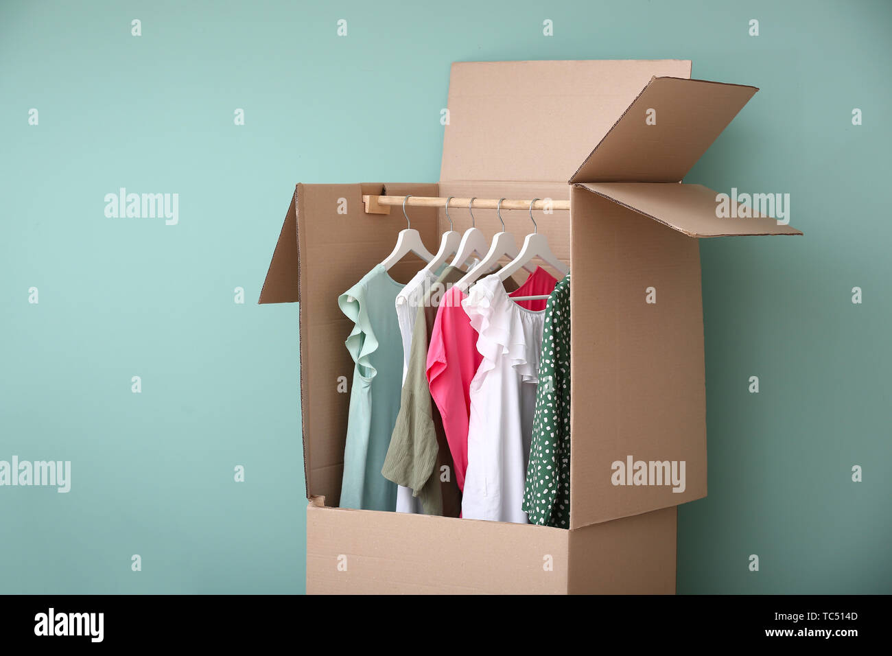 Wardrobe box with clothes on color background Stock Photo - Alamy