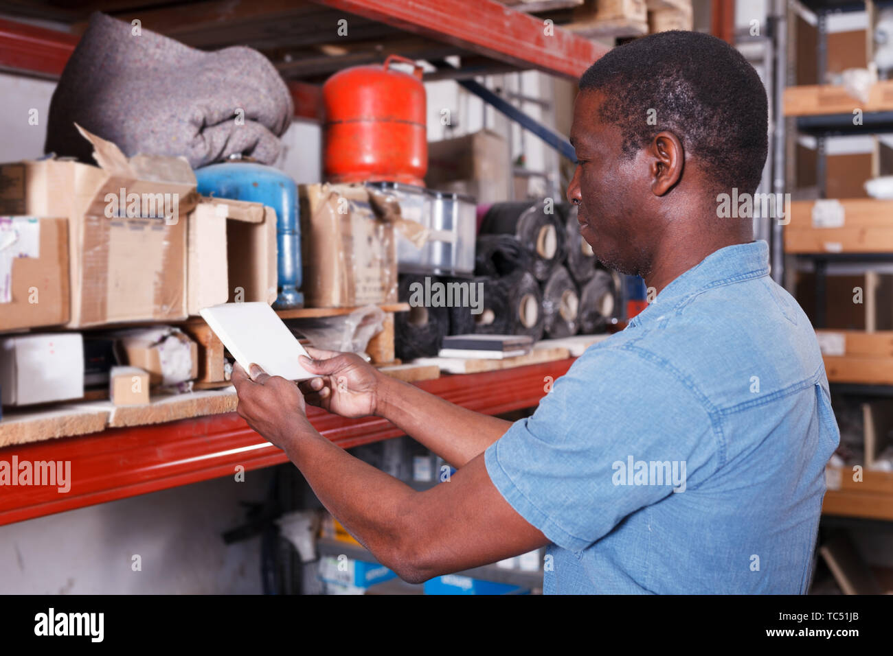 Positive African American man choosing supplies for home renovation in ...