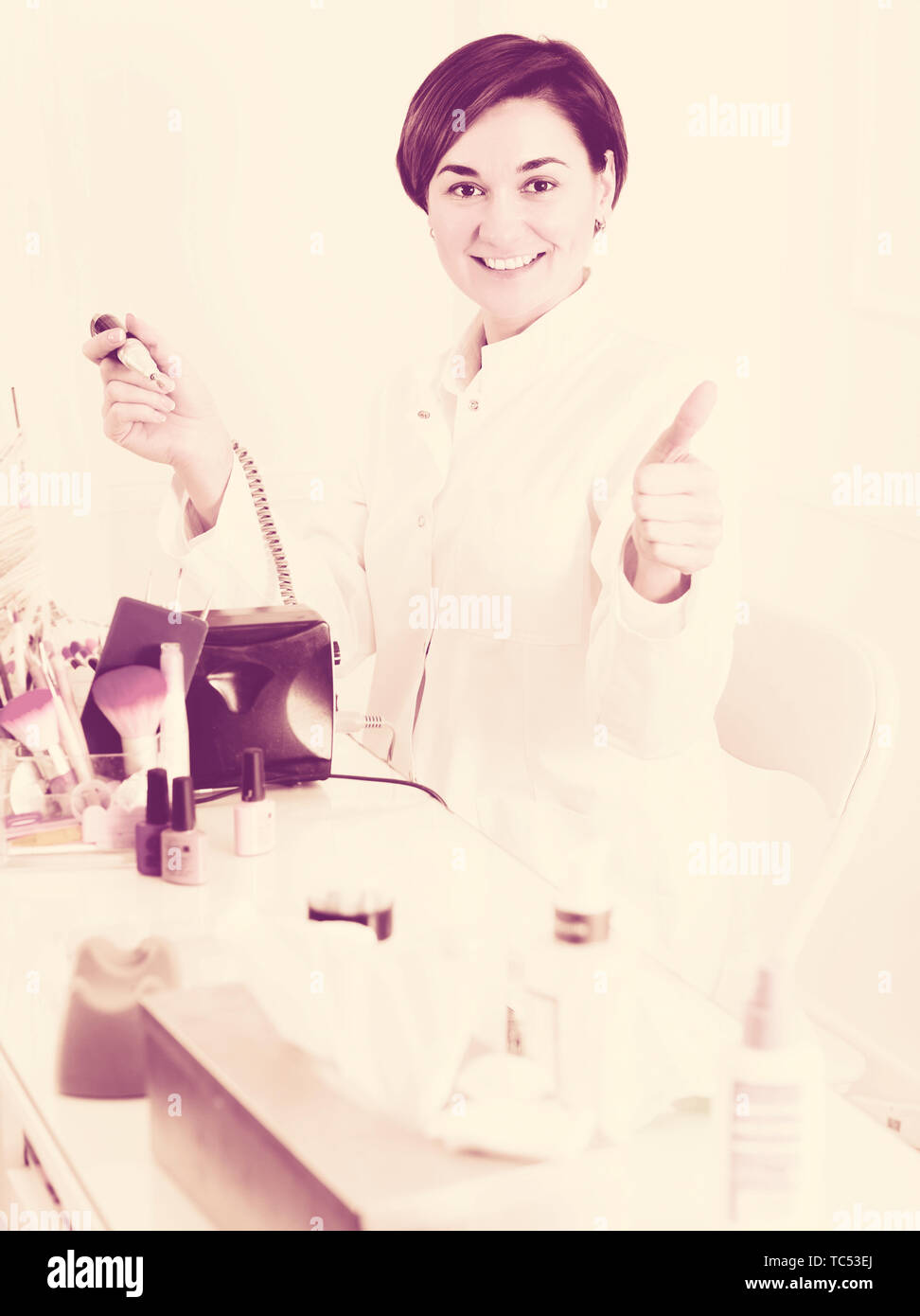 Happy young woman manicurist demonstrating her workplace in nail salon ...