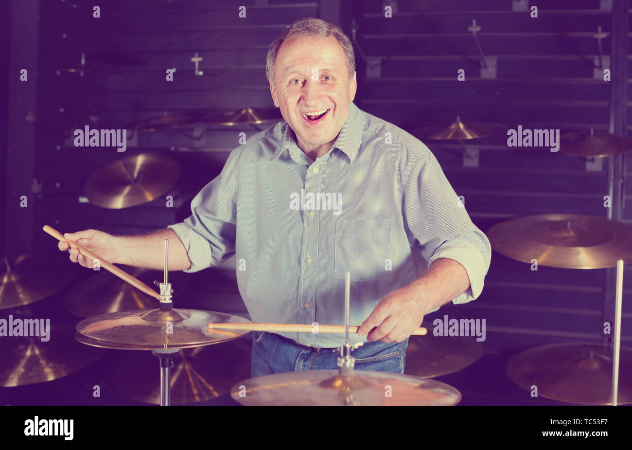 Musician glad cheerful positive smiling male is choosing drum set and ...