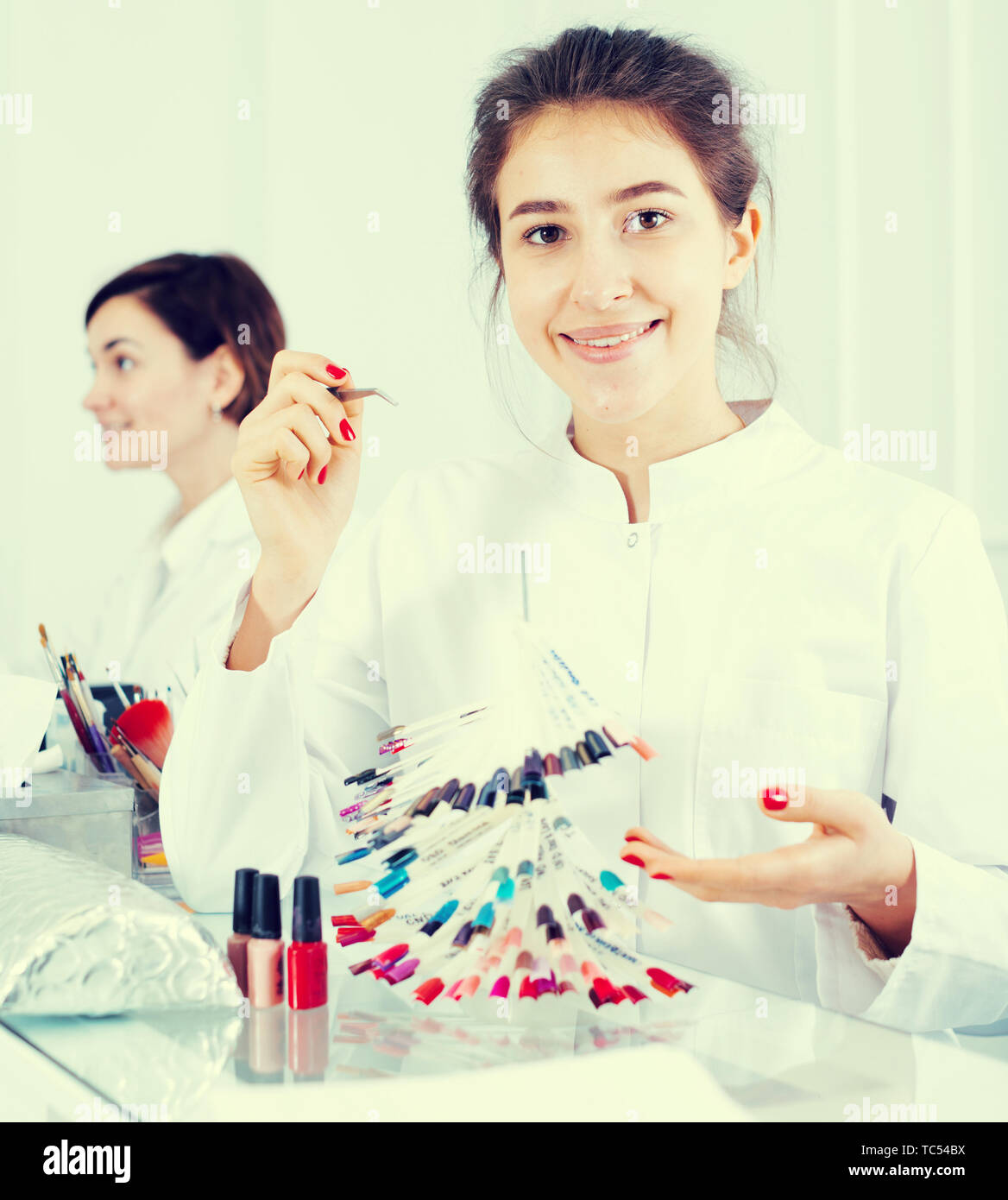 Pretty woman doing nails displaying polish color schemes in nail salon ...