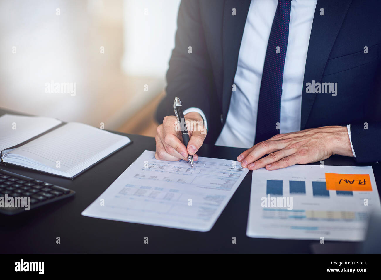 Closeup of a businessman going over paperwork while sitting at his desk ...