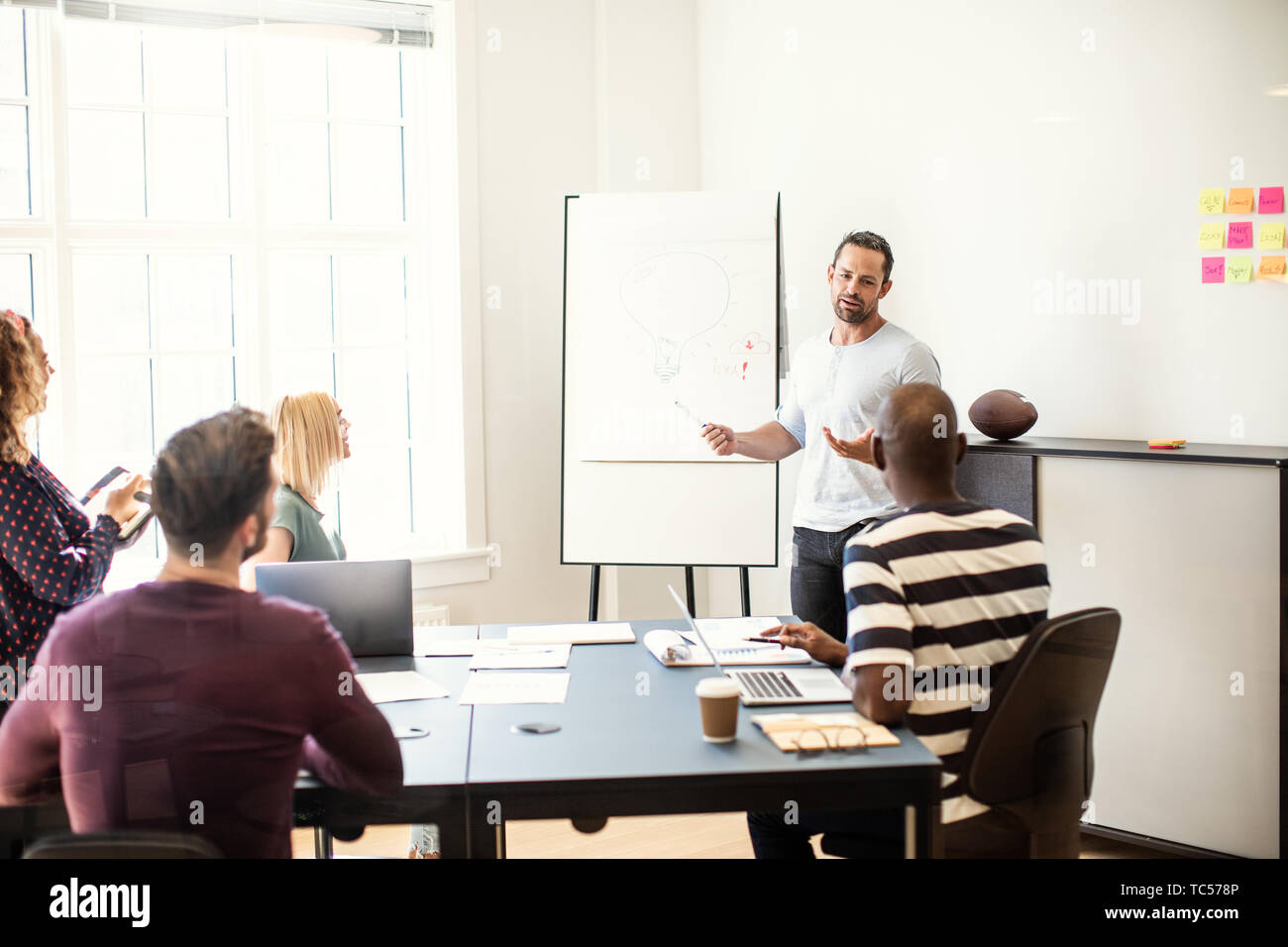Manager talking with staff sitting around a table while giving a ...
