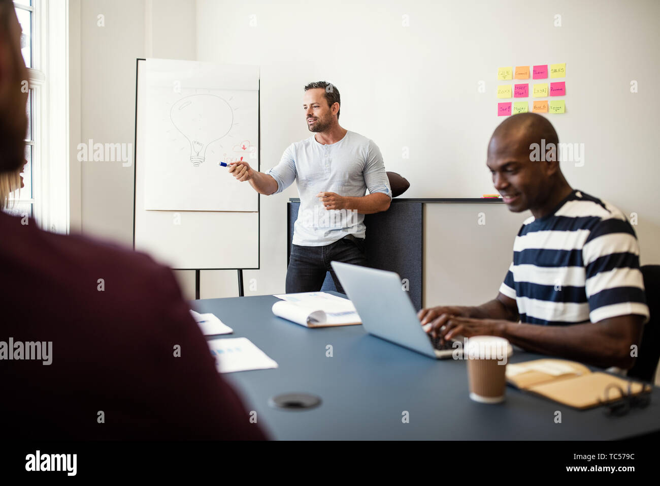 Smiling manager talking with staff sitting around a table during a ...