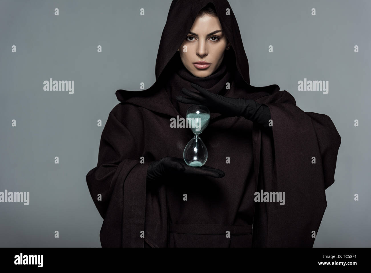front view of woman in death costume holding sand clock isolated on ...
