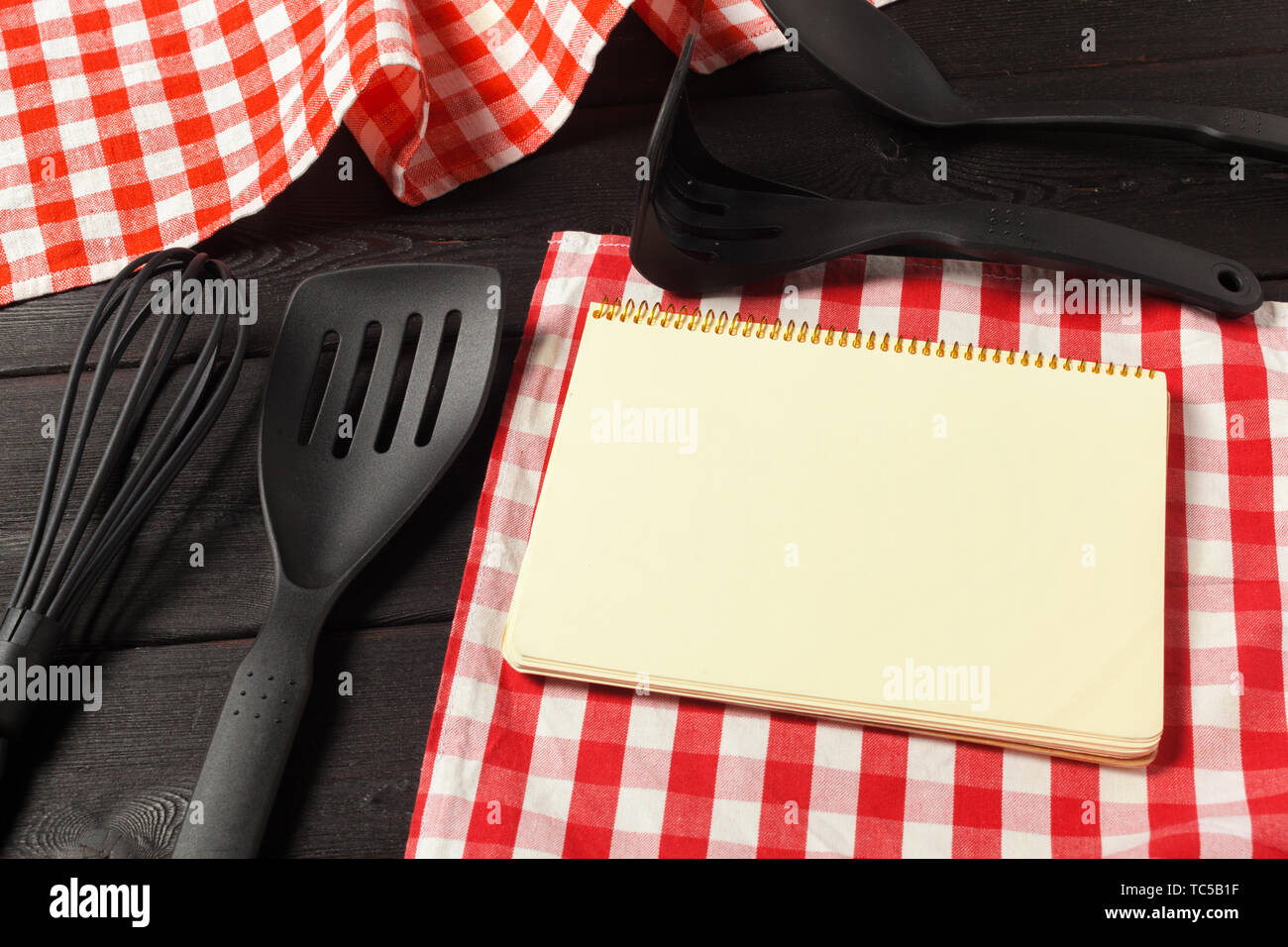 Blank sheet of opened notepad and kitchen utensils on table with ...