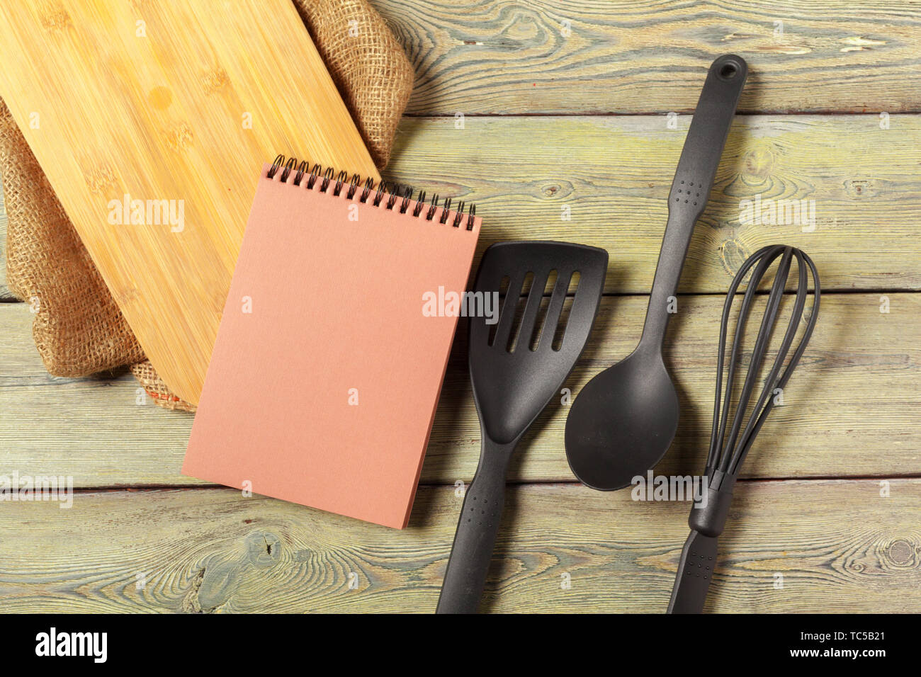 Blank sheet of opened notepad and kitchen utensils on table with ...