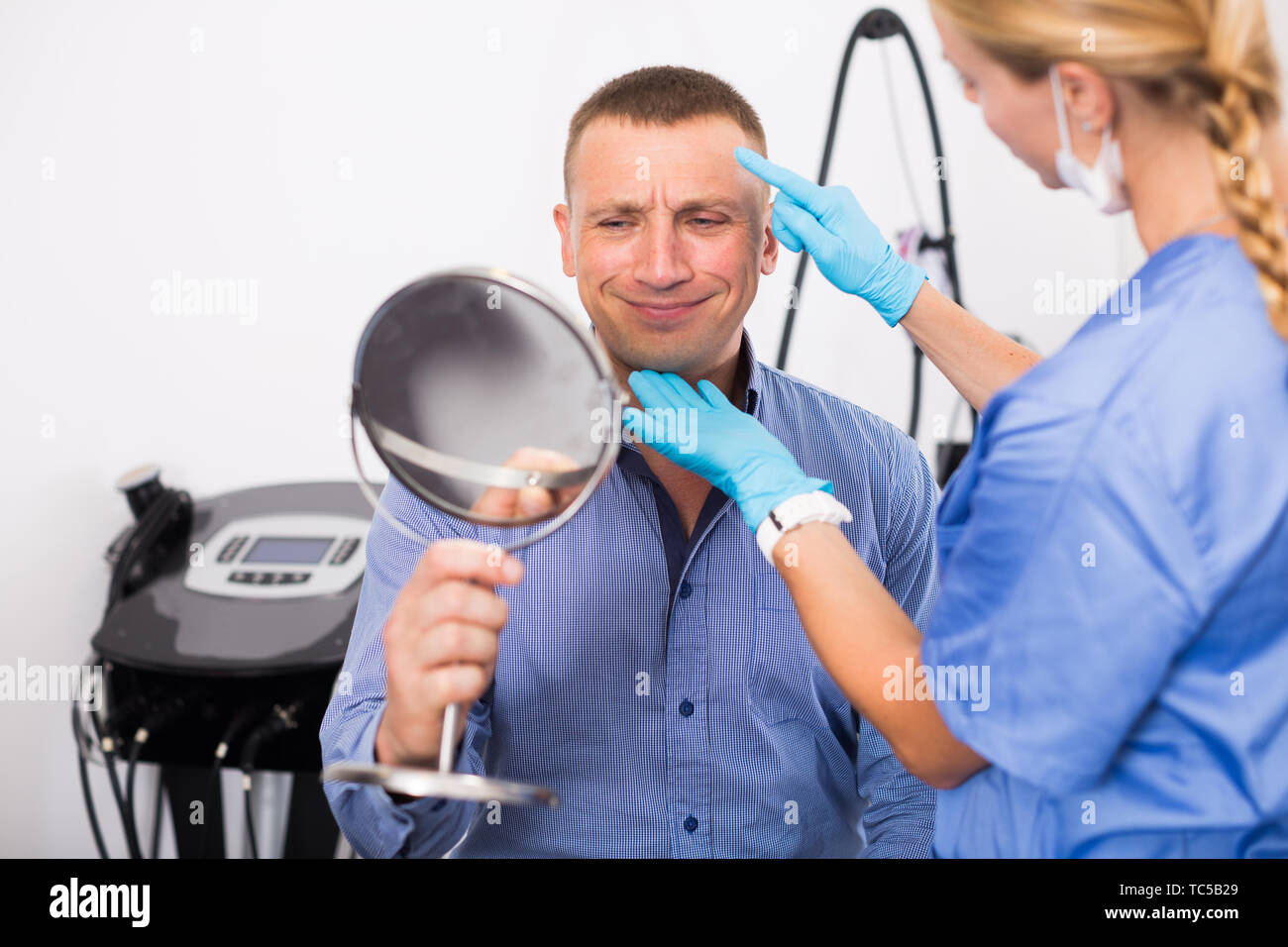 Woman doctor is examining patient behind mirror before the procedure in ...