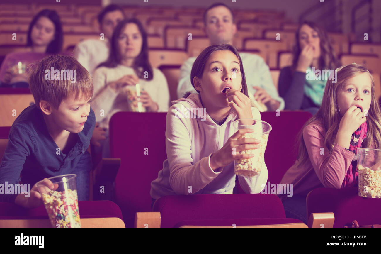 Group of different age people eating popcorn during movie in cinema ...