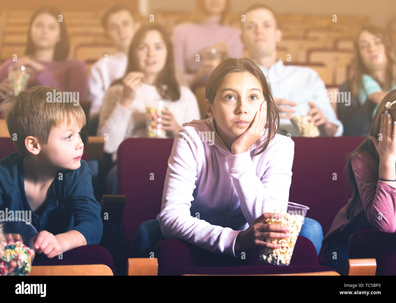 Group of different age people eating popcorn during movie in cinema ...