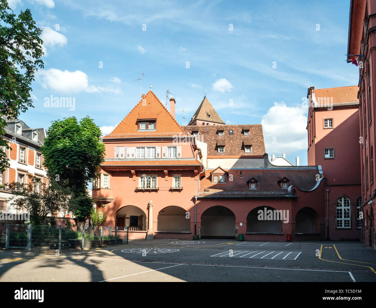 French school building in Alsace with empty yard and clear summer blue ...
