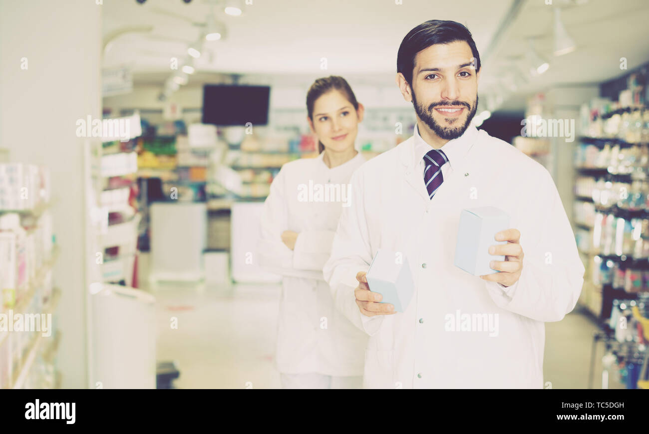 Positive male pharmacist is standing with medicines in pharmacy Stock ...