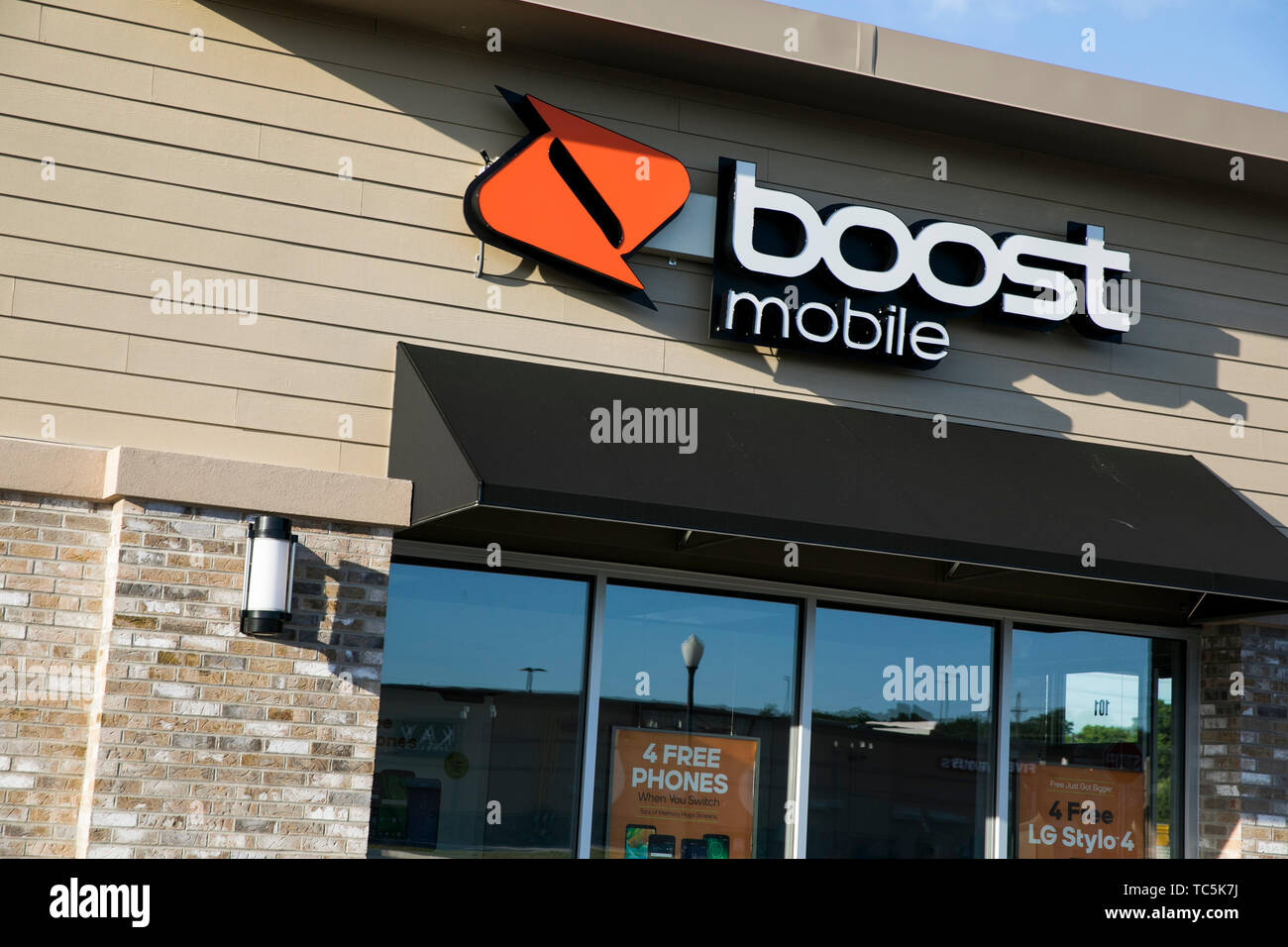 A logo sign outside of a Boost Mobile retail store location in ...