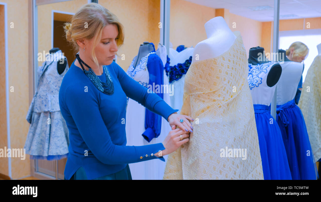 Fashion designer working with new model tailoring dress on mannequin ...
