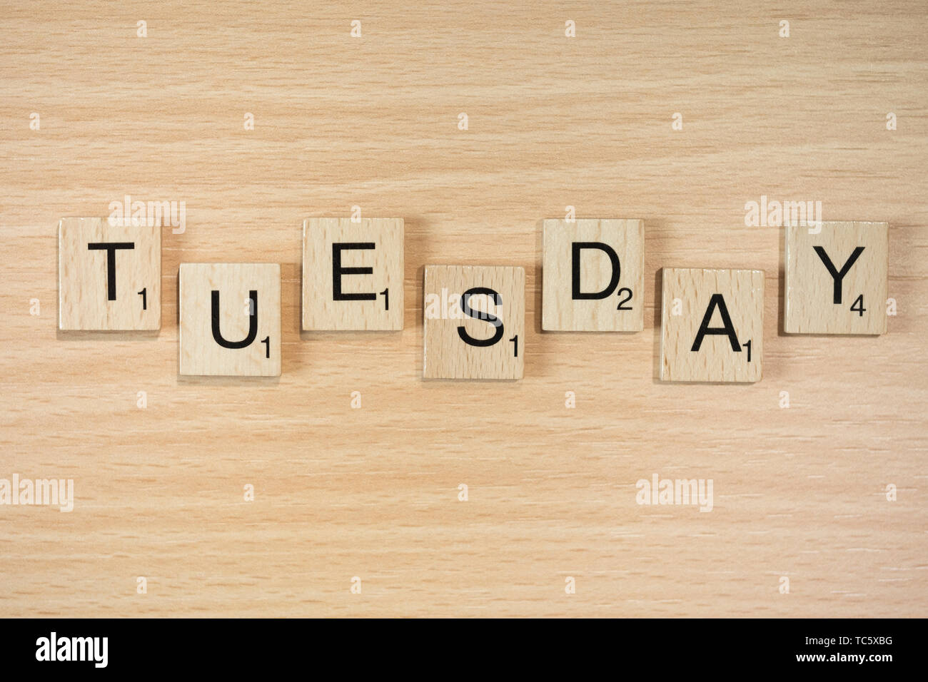 The word Tuesday, spelt out using wooden tiles on a wood effect ...