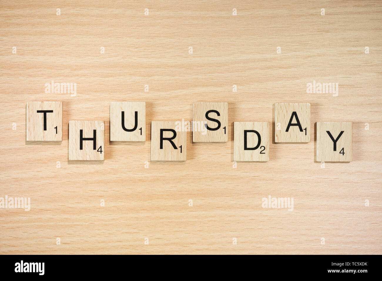 The word Thursday, spelt out using wooden tiles on a wood effect ...