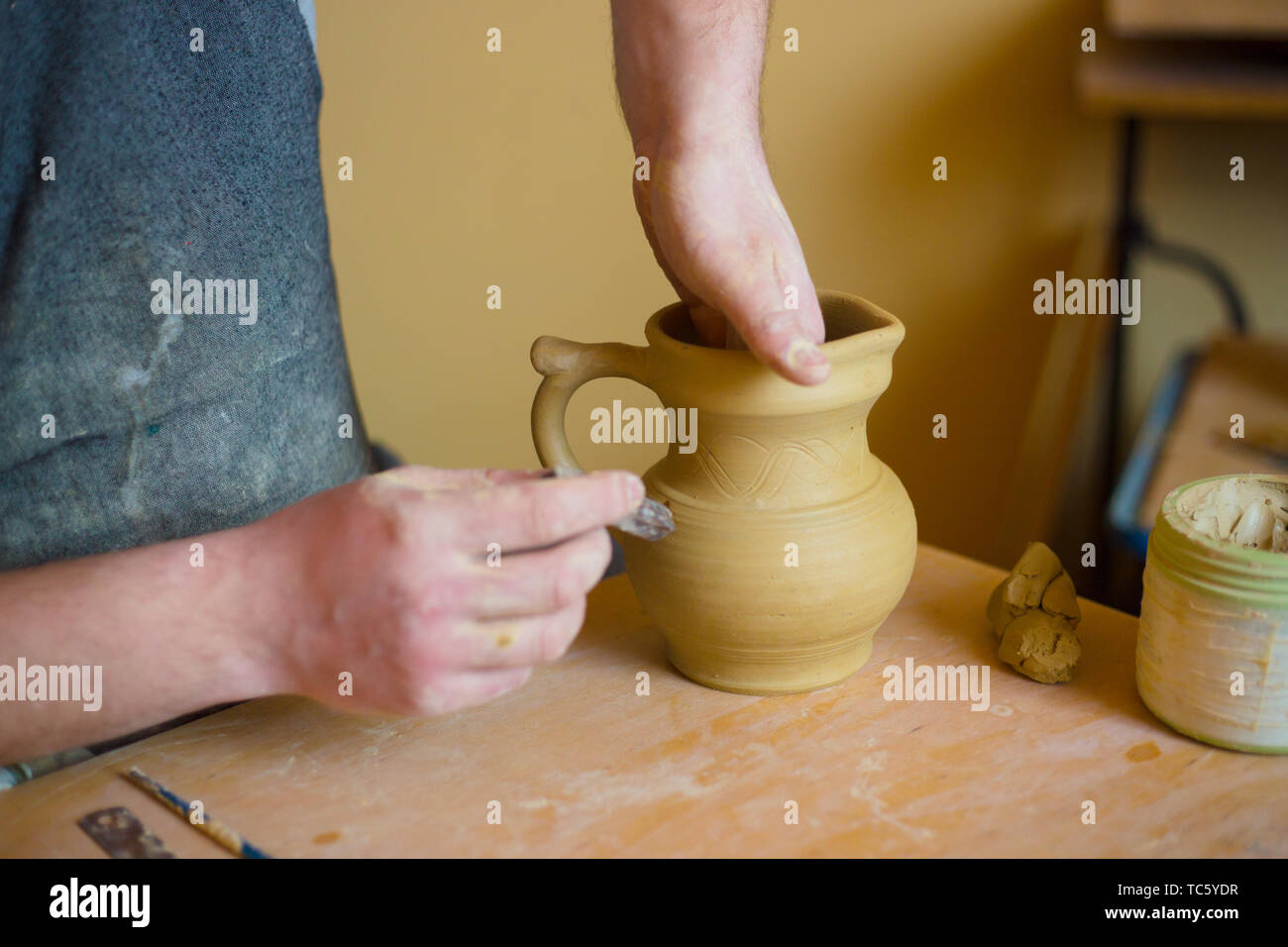 Professional potter making pattern on clay jar with special tool in ...