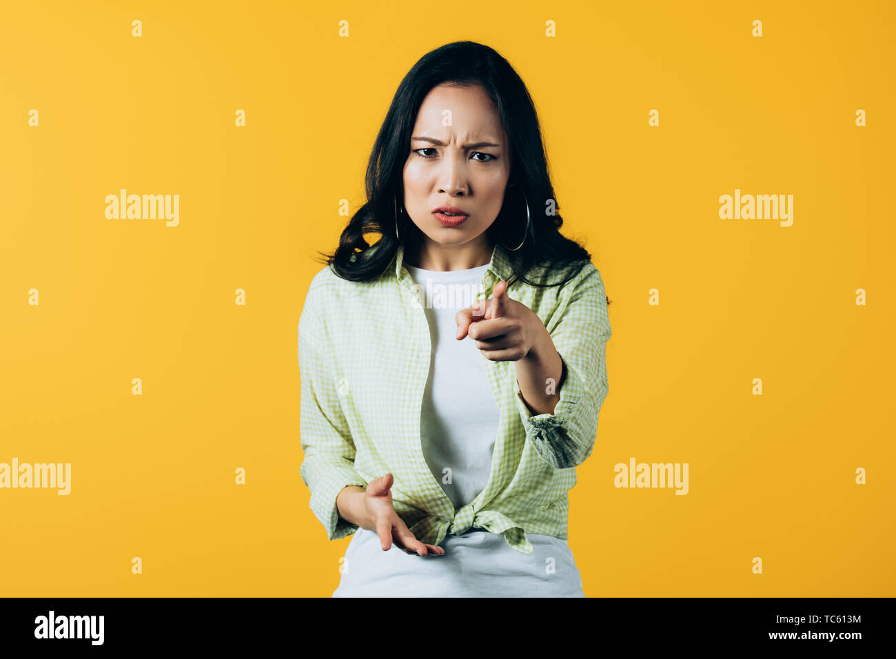emotional angry asian girl pointing at you isolated on yellow Stock ...
