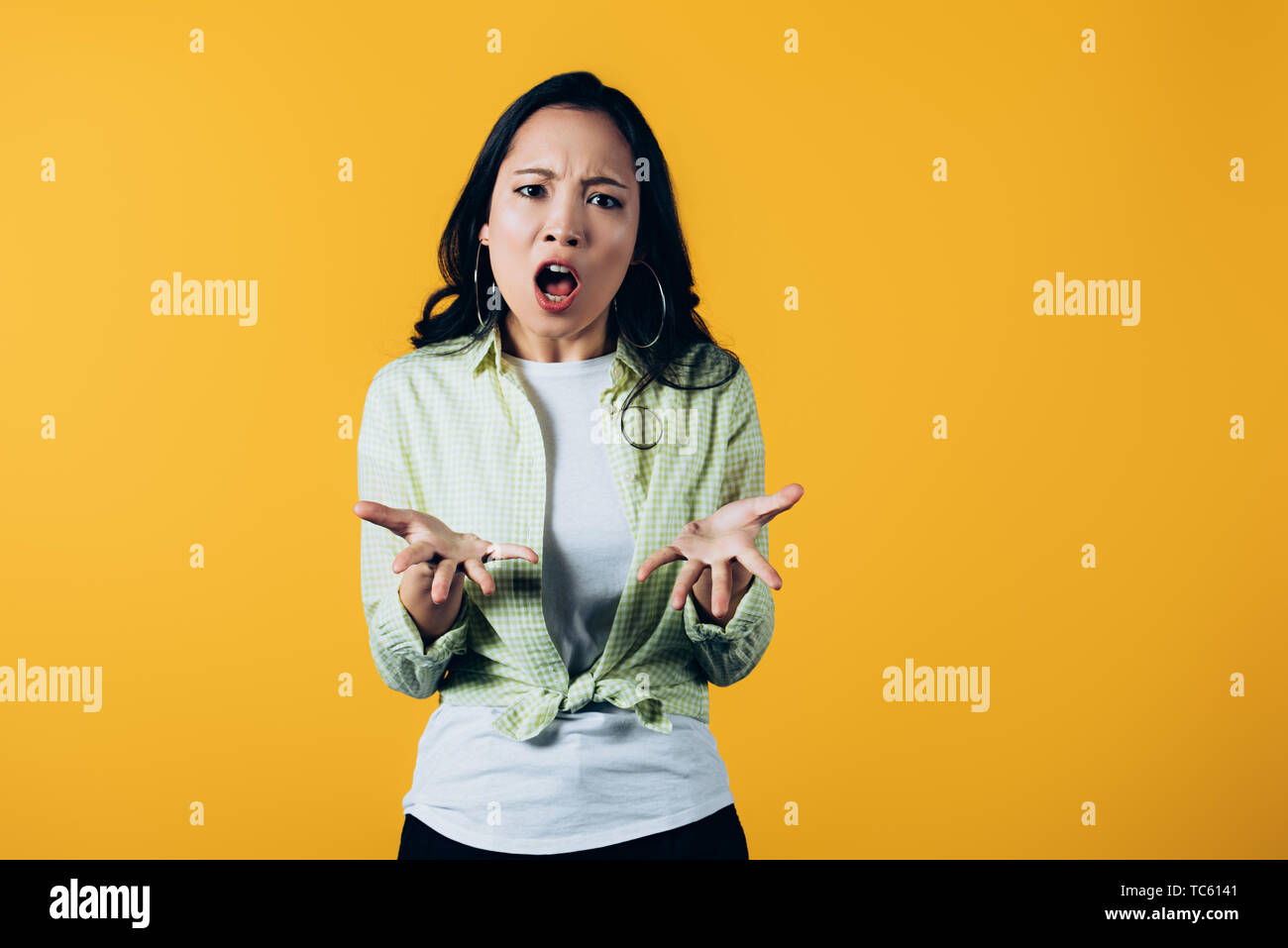 aggressive asian woman yelling isolated on yellow Stock Photo - Alamy