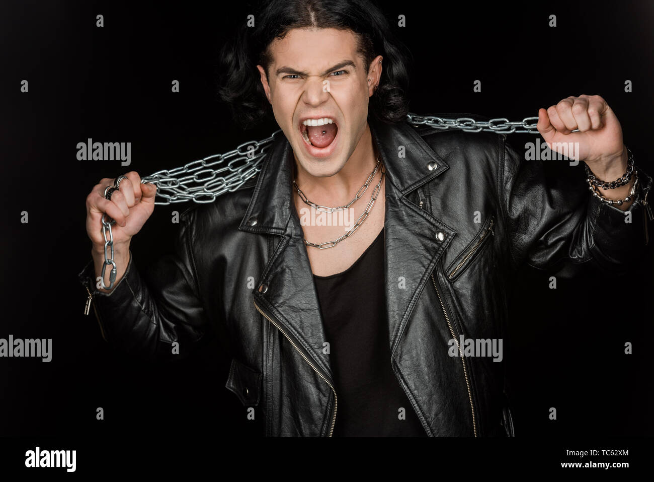 angry man screaming while holding metallic chains isolated on black ...