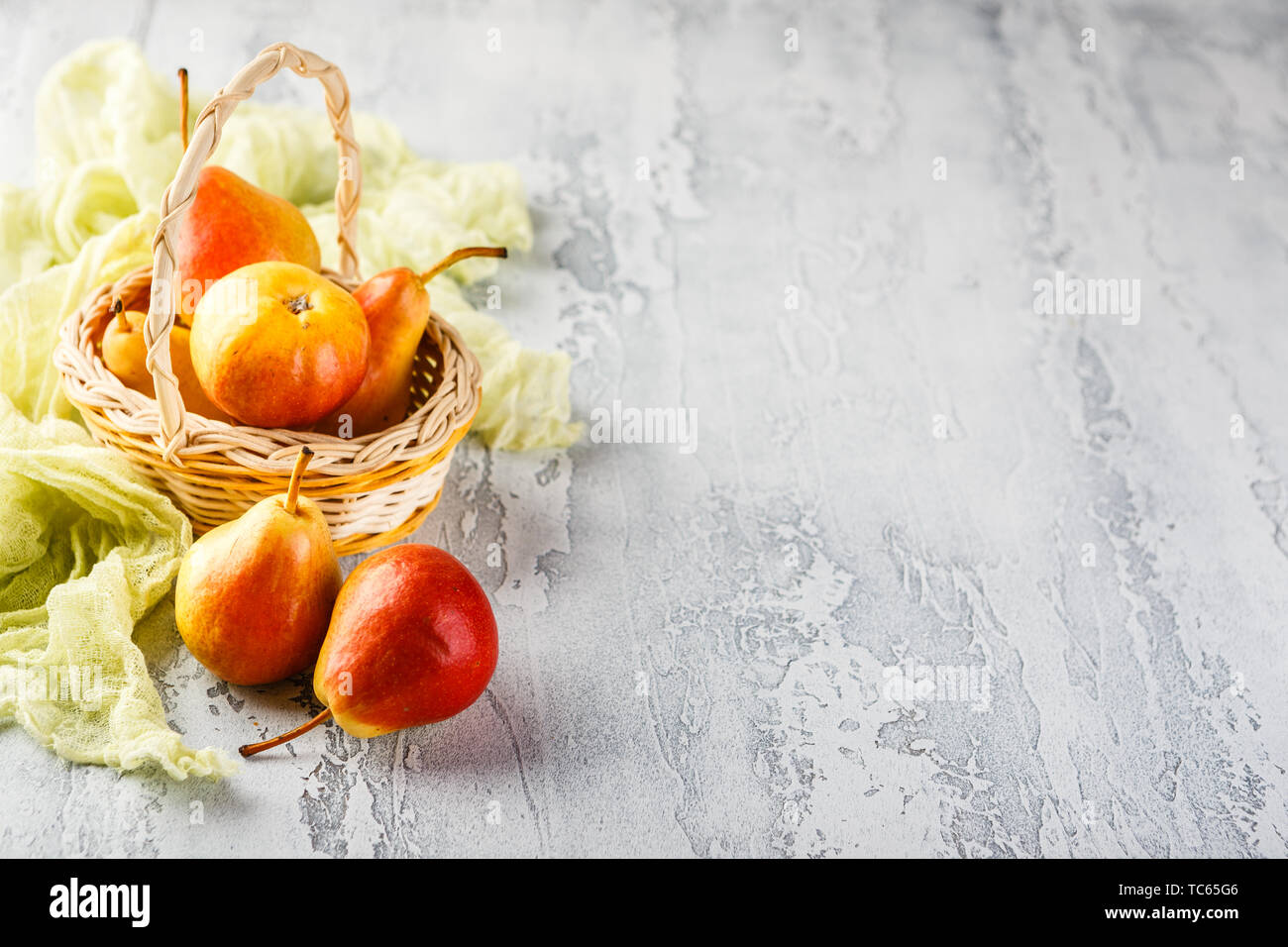 Fresh bio yellow and red pears in basket on the grey background. Space ...