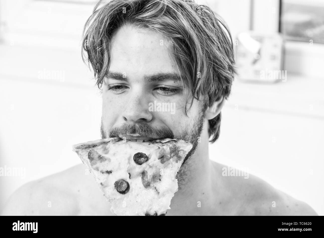 Handsome man holds a piece of pizza in his hands and is about to eat it ...