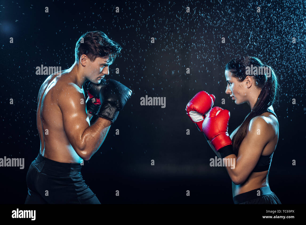 Side view of two boxers in boxing gloves training together under water ...
