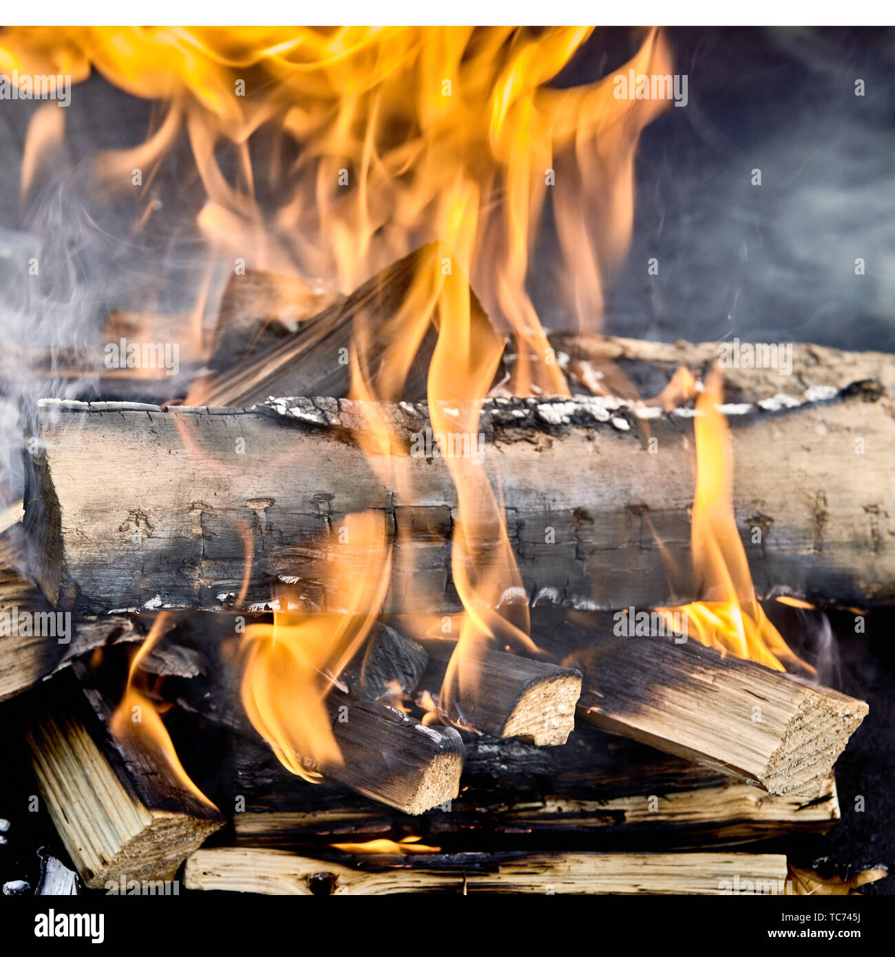 Close up on multiple flaming wooden logs burning in hot barbecue fire ...