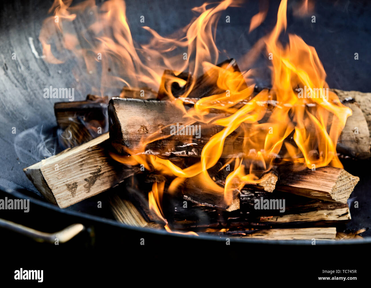 Freshly lit barbecue fire with logs of burning wood over small chips of ...