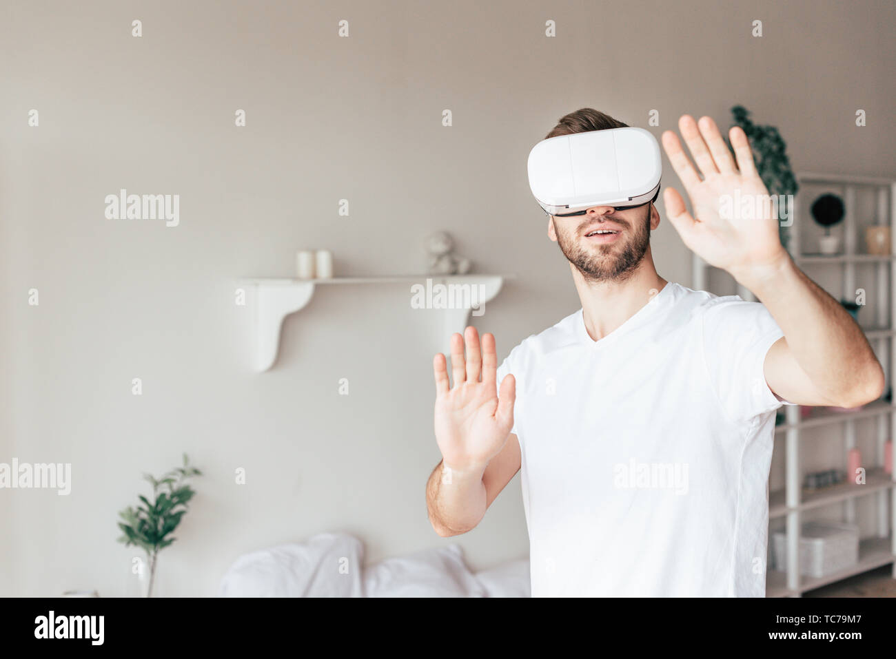 emotional man in vr headset waving hands in bedroom Stock Photo - Alamy